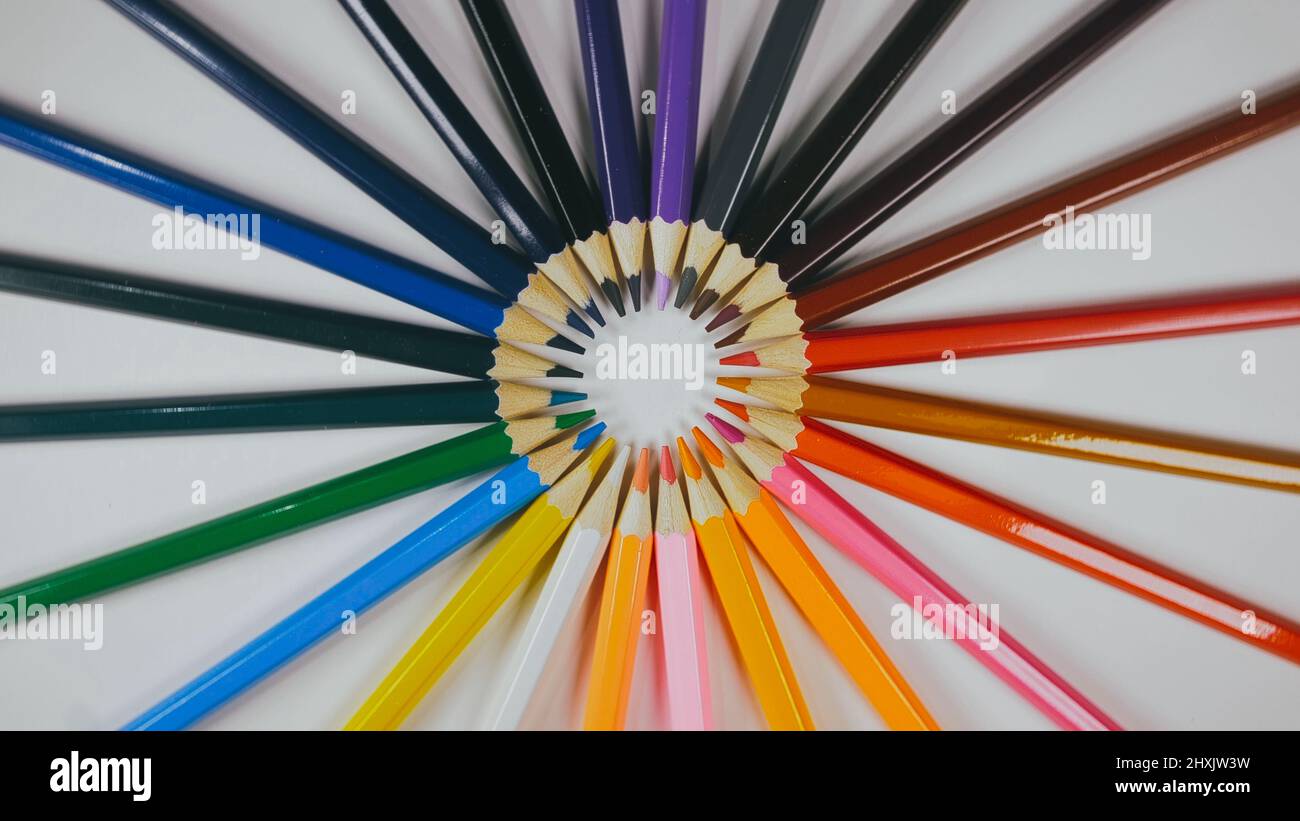 Many colored pencils are arranged around the edges of the image as a ...
