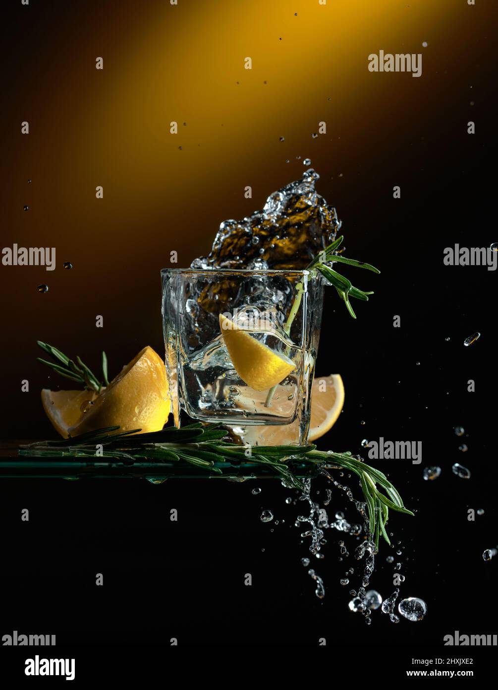 Gin and tonic cocktail with lemon and rosemary. A slice of lemon falls ...
