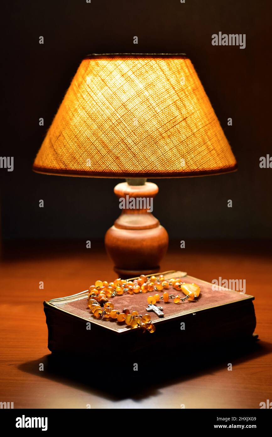 Soft light of table lamp, old book (prayer book or Bible) and amber ...