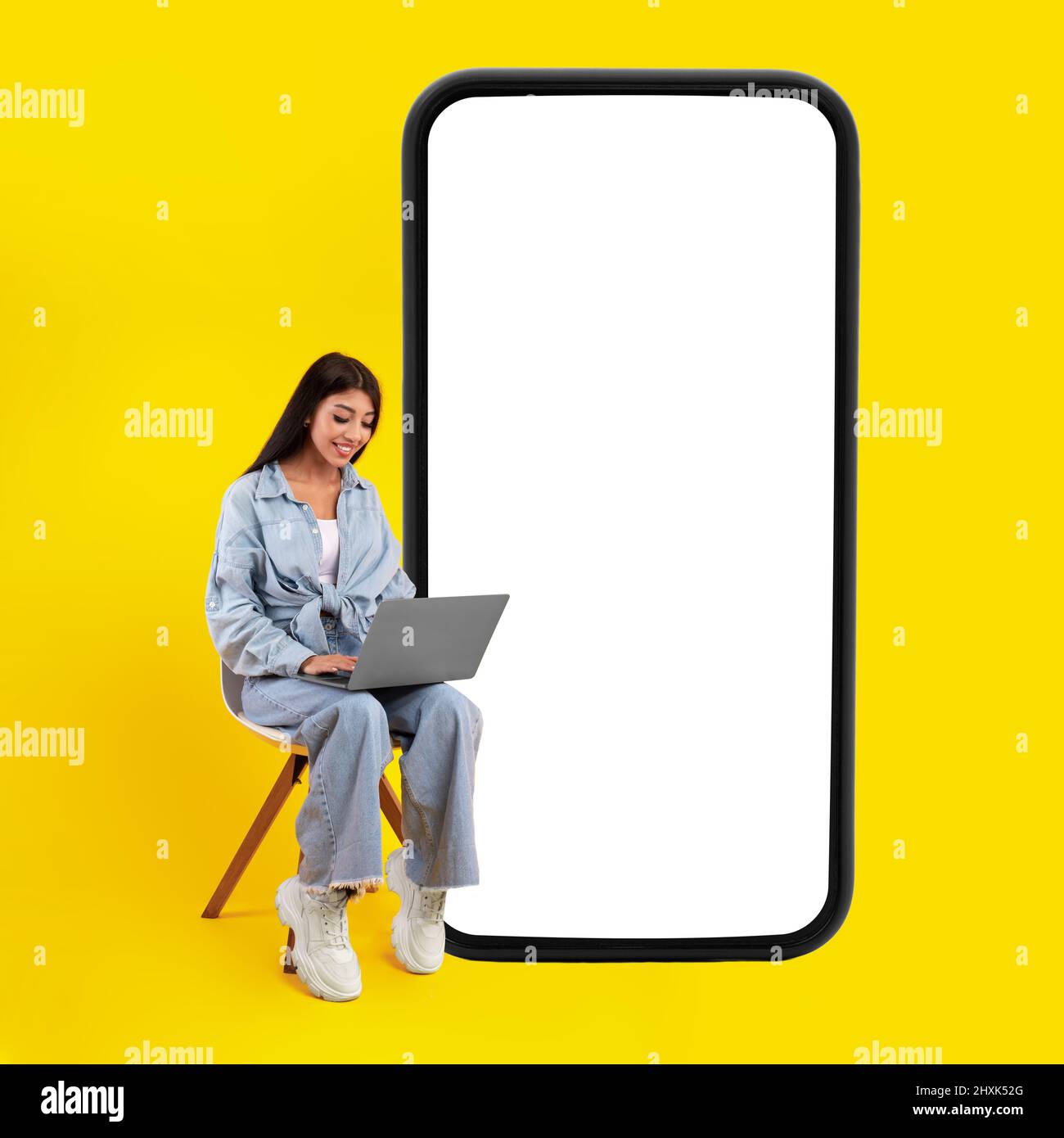 Happy lady using pc sitting near big mobile phone screen Stock Photo ...