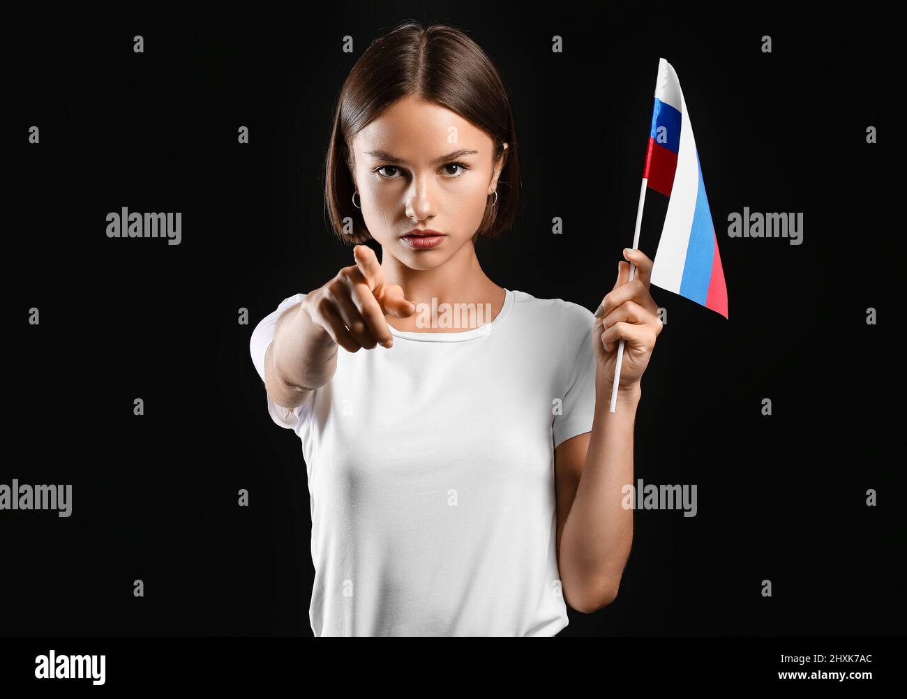 Beautiful young woman with flag of Russia pointing at viewer on dark ...