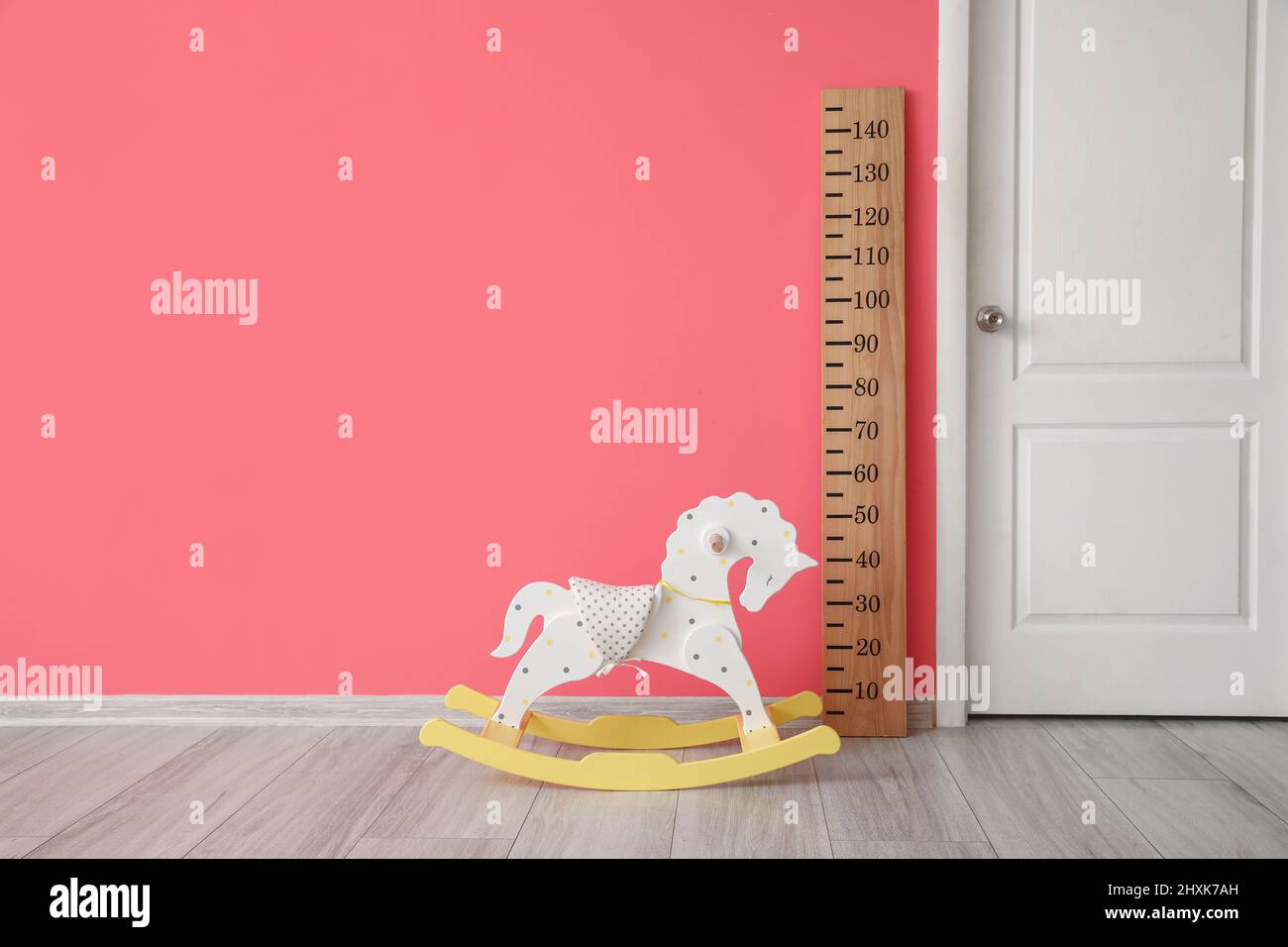 Big ruler for height measuring, rocking horse and white door near color ...