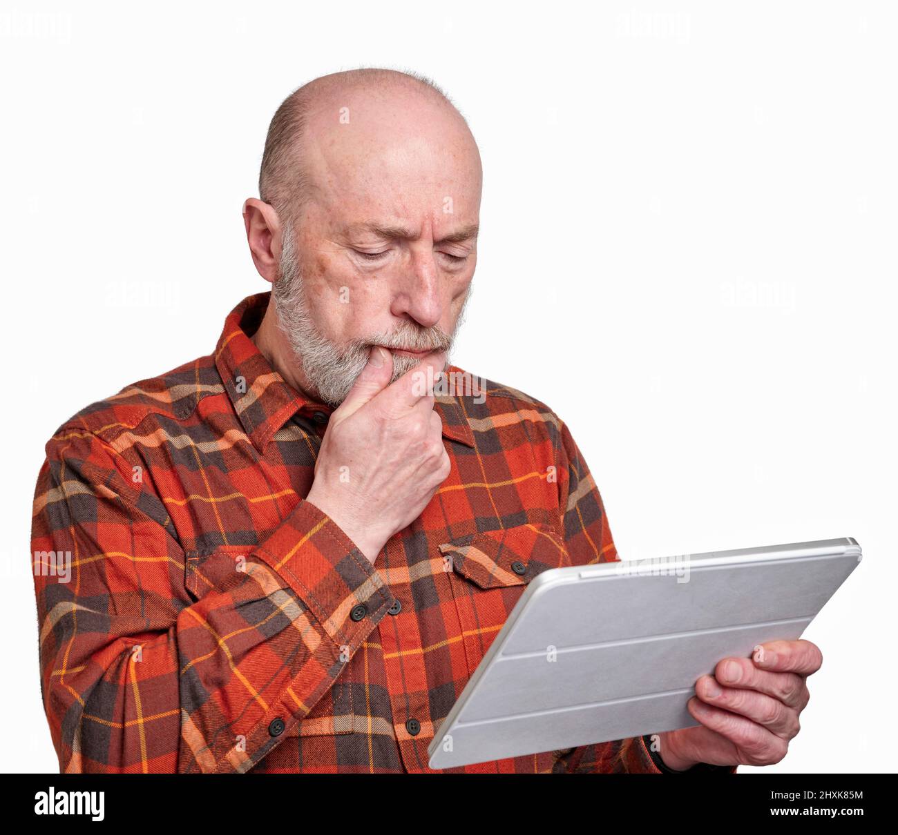 senior man is reading or watching news on a digital tablet and looks ...
