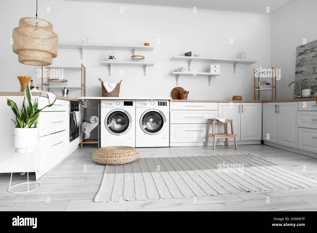 Interior of light kitchen with washing machines, laundry basket and ...