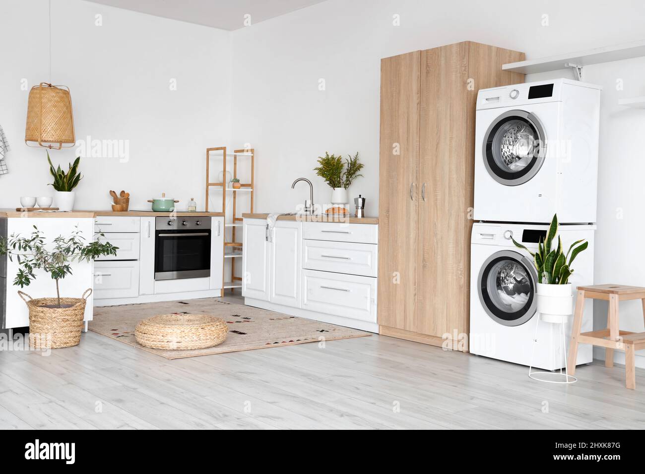 Interior of light kitchen with washing machines, white counters and ...