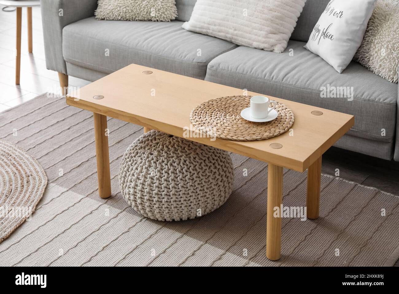 Modern table with sofa and pouf in interior of room Stock Photo - Alamy