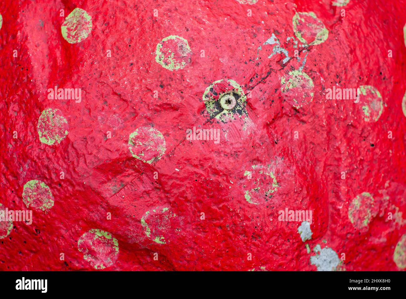 Top view of weathered hand painted red stone stool with faded green ...