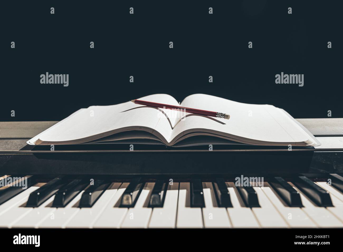 Open notepad on piano keys in the dark, copy space Stock Photo - Alamy
