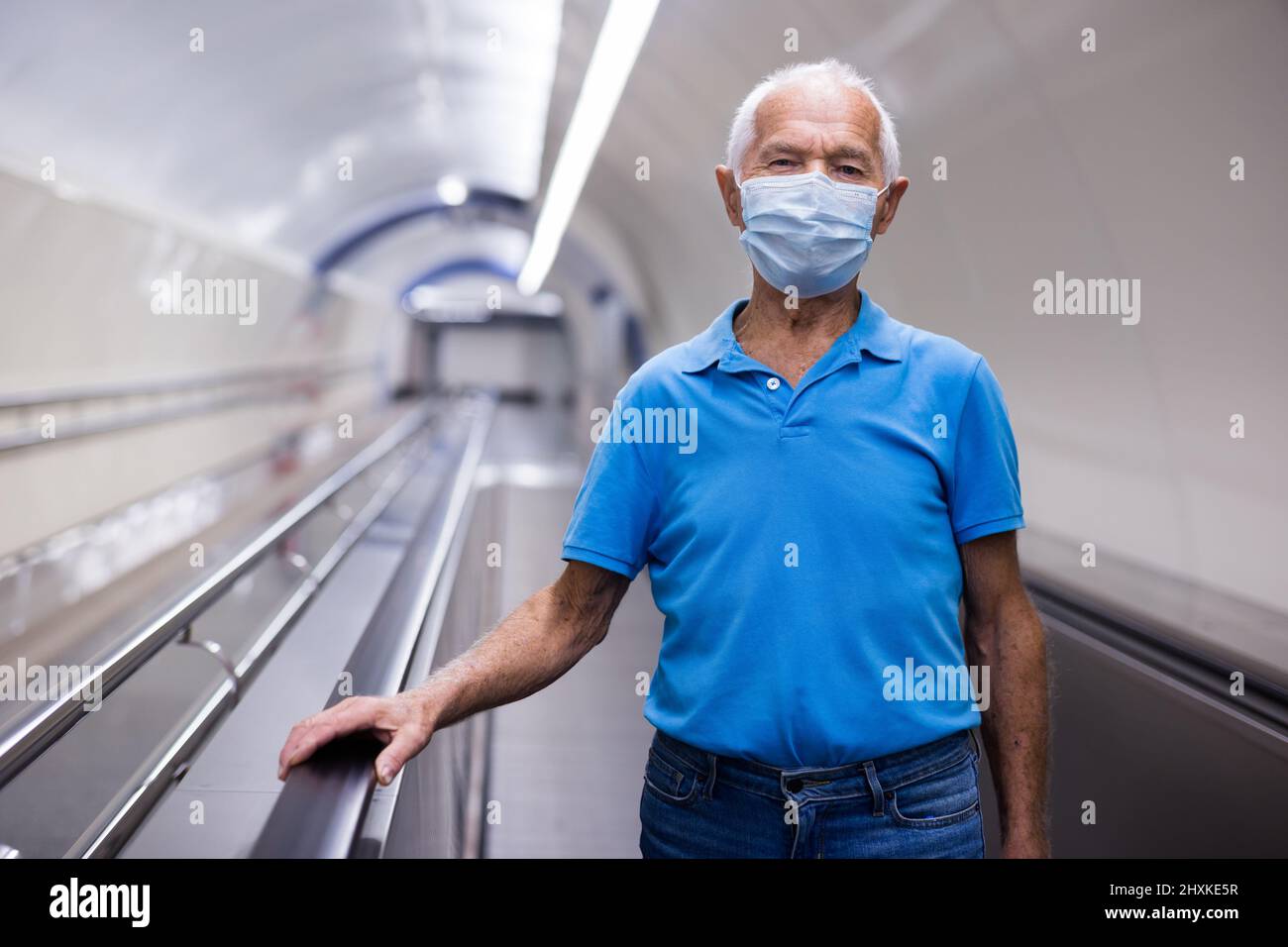 Senior man in mask standing on moving walkway Stock Photo - Alamy
