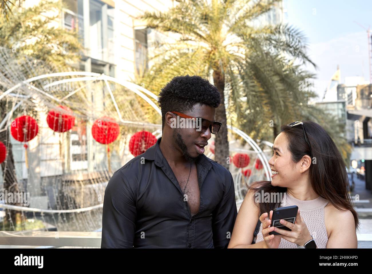 Multiethnic friends chatting while using the mobile outside a mall in ...