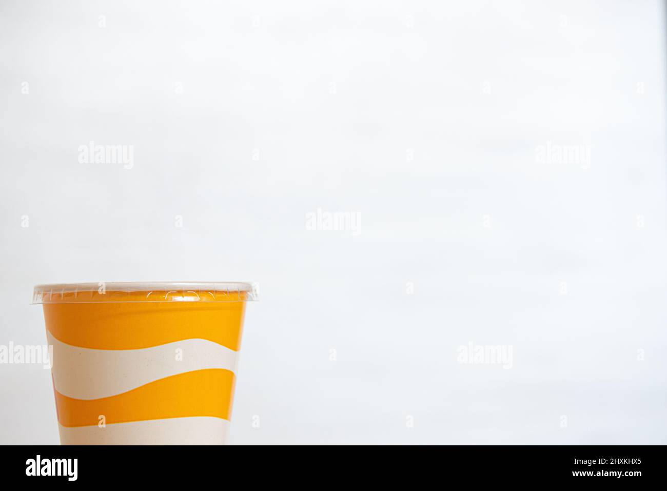 Yellow and white striped plastic cup for soft drinks with copy space ...