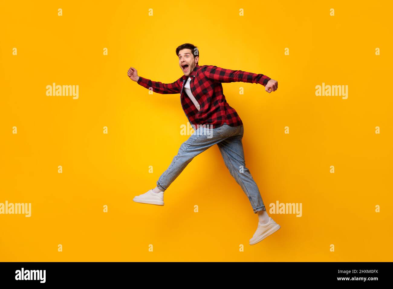Excited young man jumping up at orange studio Stock Photo - Alamy