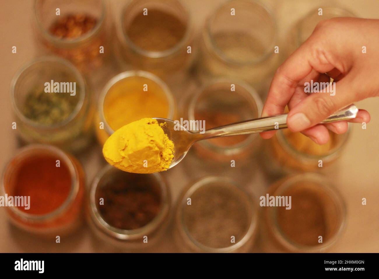 Yellow turmeric powder in spoon holding by woman hand Stock Photo - Alamy