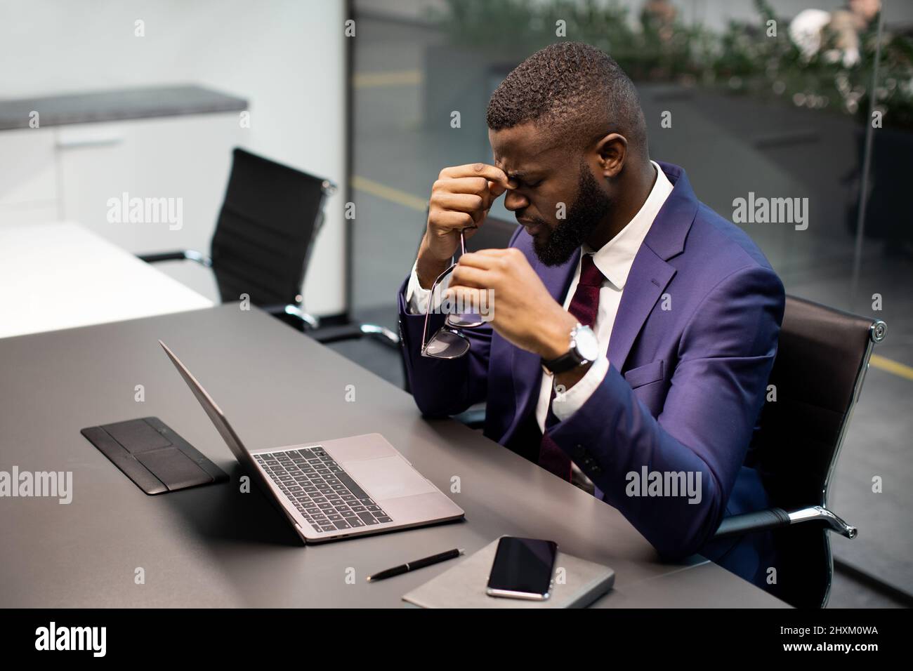 Tired black CEO working at office, having migraine Stock Photo - Alamy