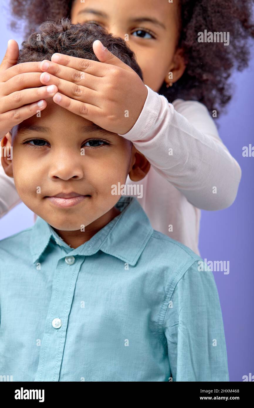 Portrait of cheerful joyful carefree little girl and boy covering eye ...