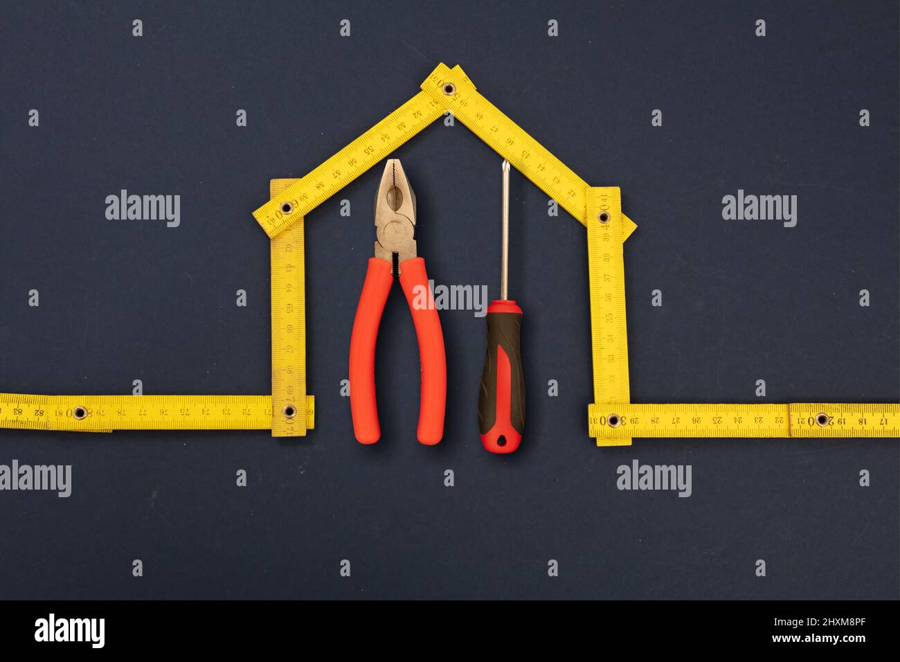 Home repair. Hand tools under house shape yellow wooden measure, black ...