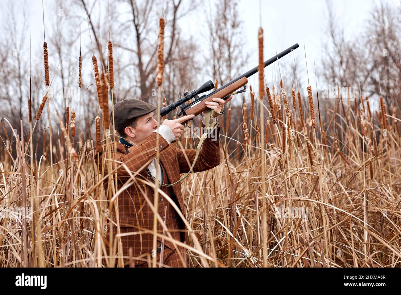 european caucasian hunter is hunting in forest, looking through the ...