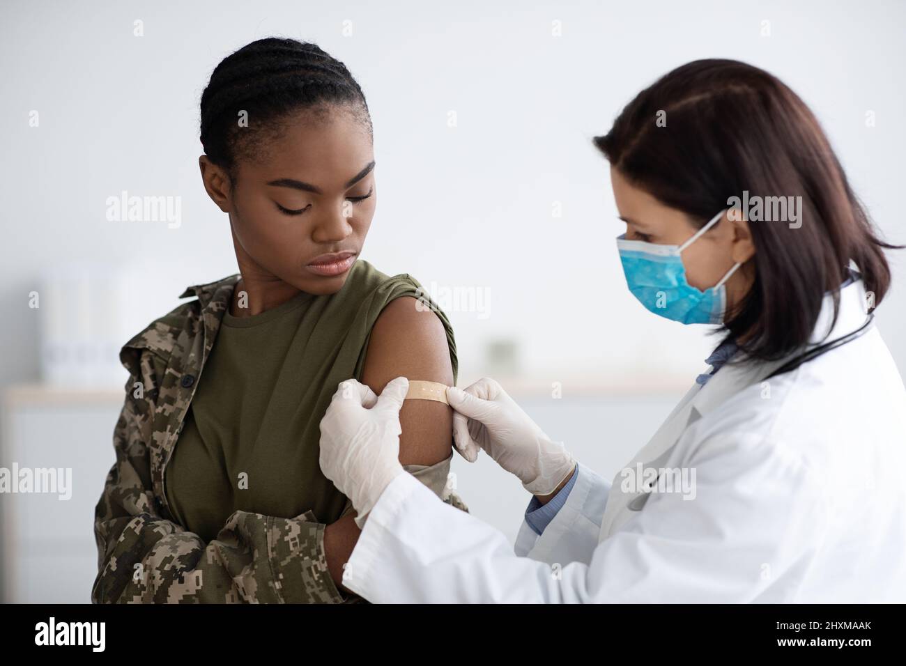 Female Doctor Applying Sticking Plaster On Black Military Lady's ...