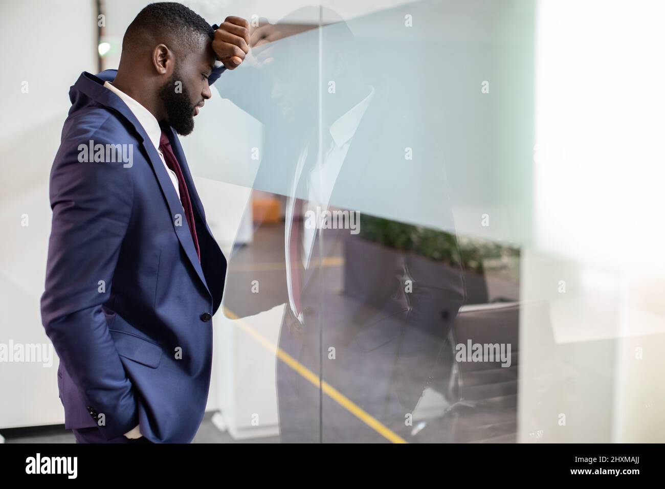 Exhausted black businessman leaning on window glass Stock Photo - Alamy