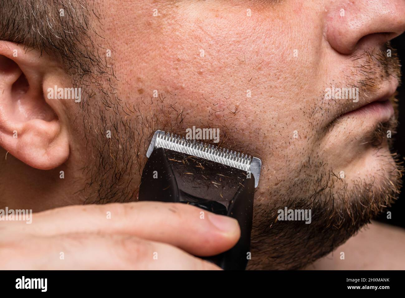 Man shaving or trimming his beard using a hair clipper Stock Photo - Alamy