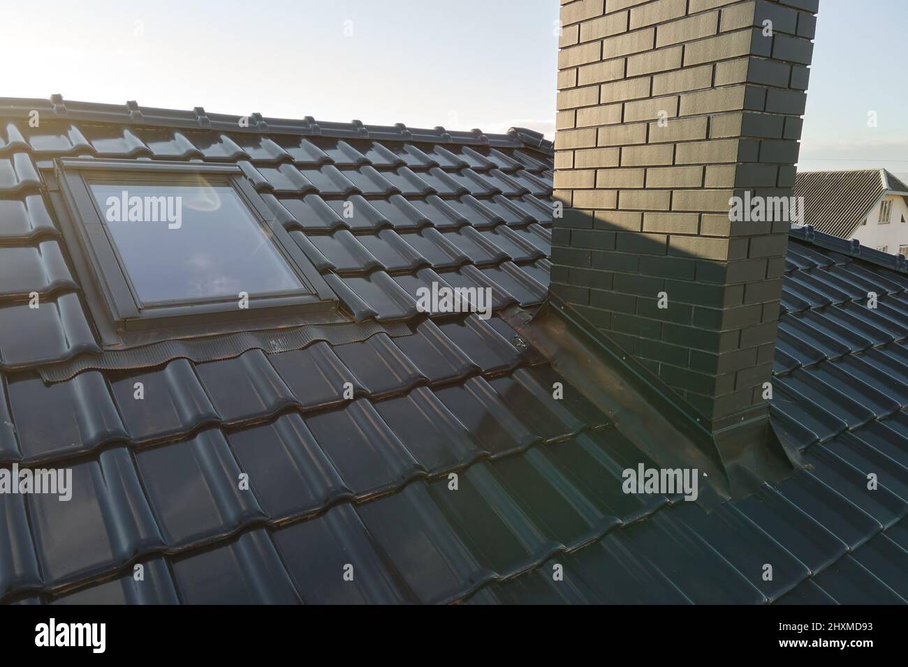 Closeup of attic window and brick chimney on house roof top covered ...