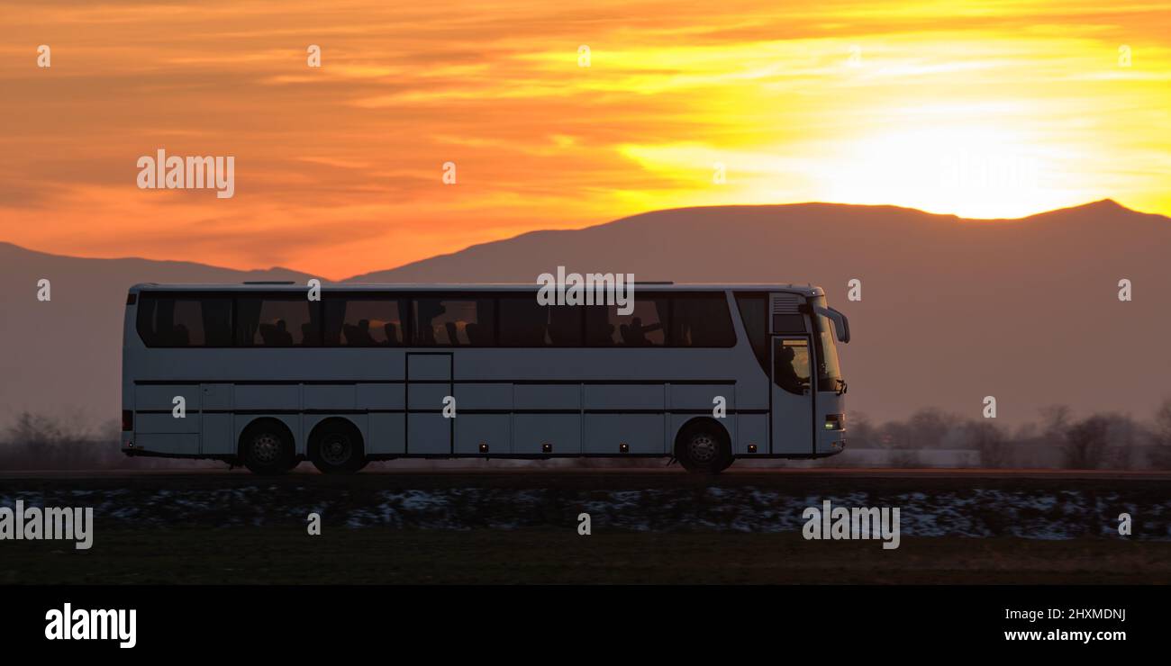 Intercity passenger bus driving on highway road in evening Stock Photo ...