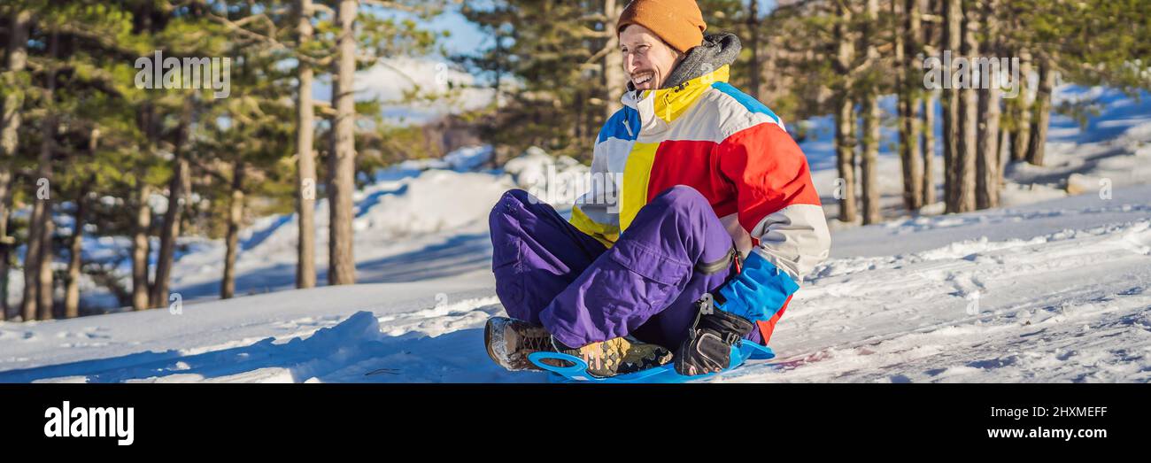 Cheerful man sledding down a snowy slope in full speed BANNER, LONG ...