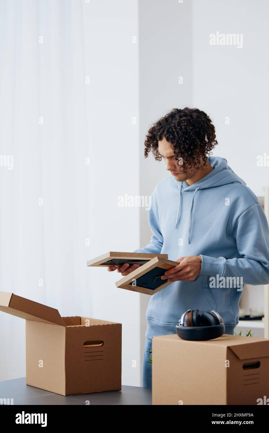 handsome guy unpacking things from boxes in the room sorting things out ...