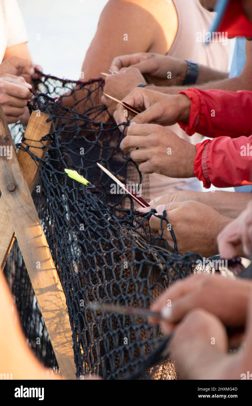 Group of fishermen repairing the fishing net , working hands close up ...
