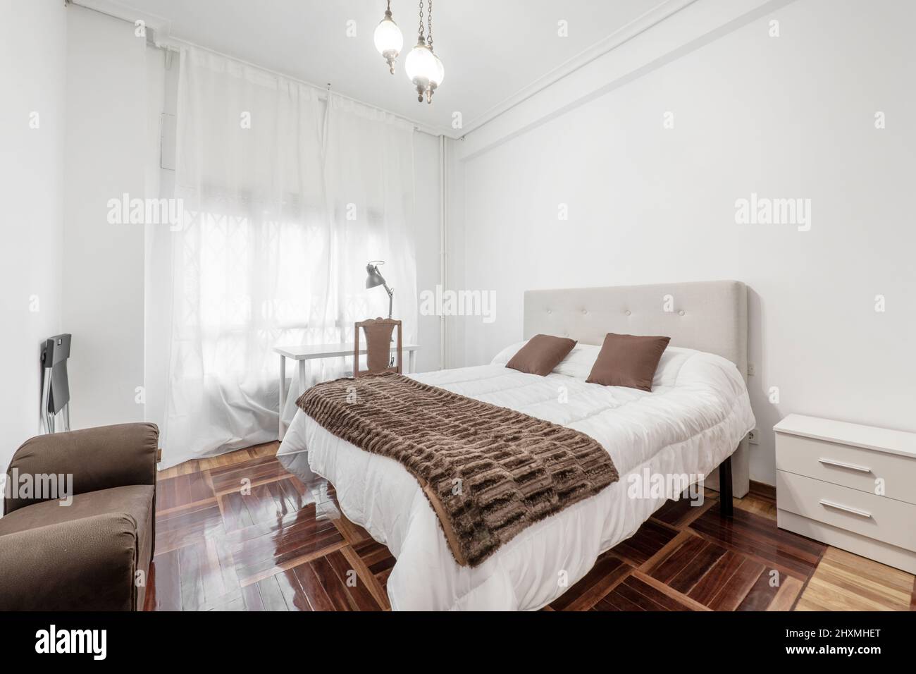 Bedroom with bed with white duvet, brown blanket with matching cushions ...