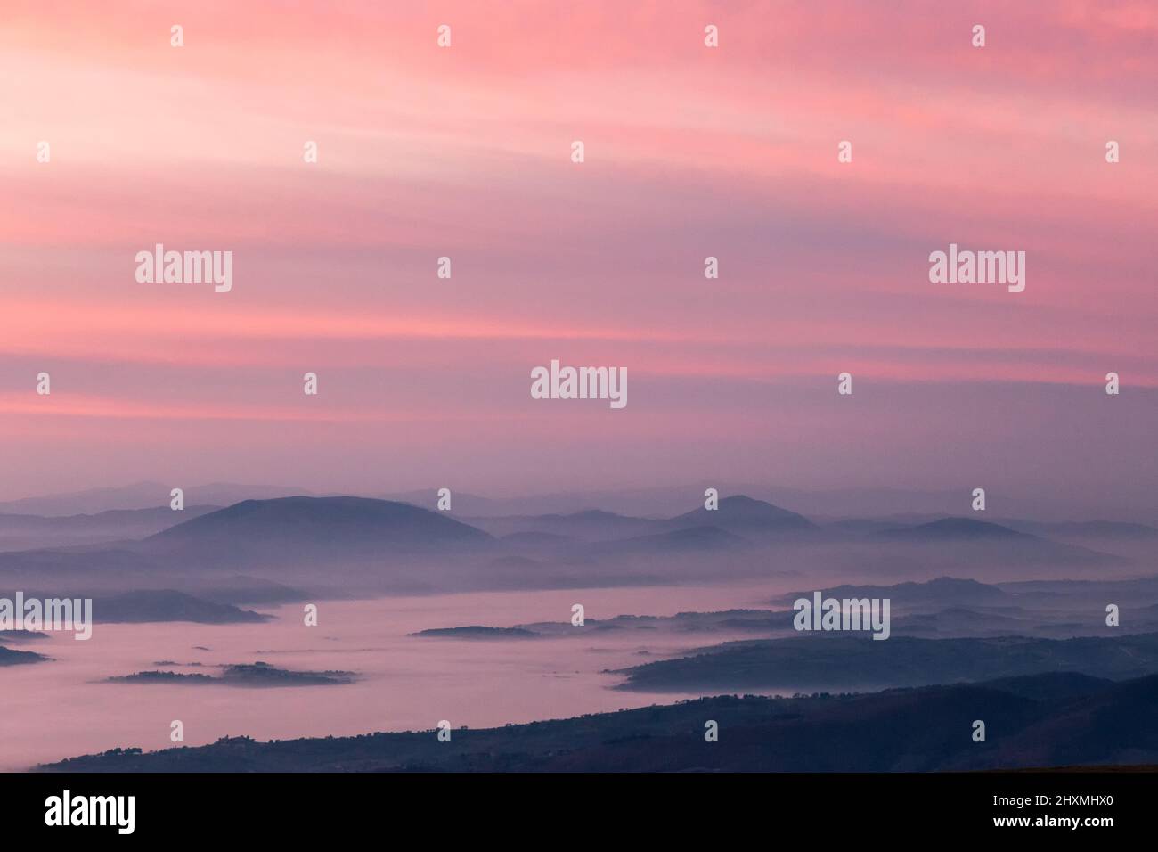Mist and fog between valley and layers of mountains and hills at sunset ...