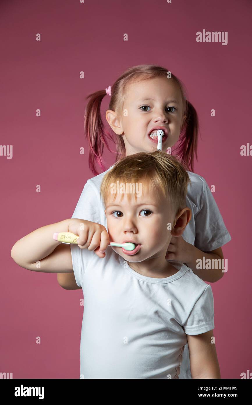 Smiling caucasian little boy and girl cleaning his teeth with electric ...