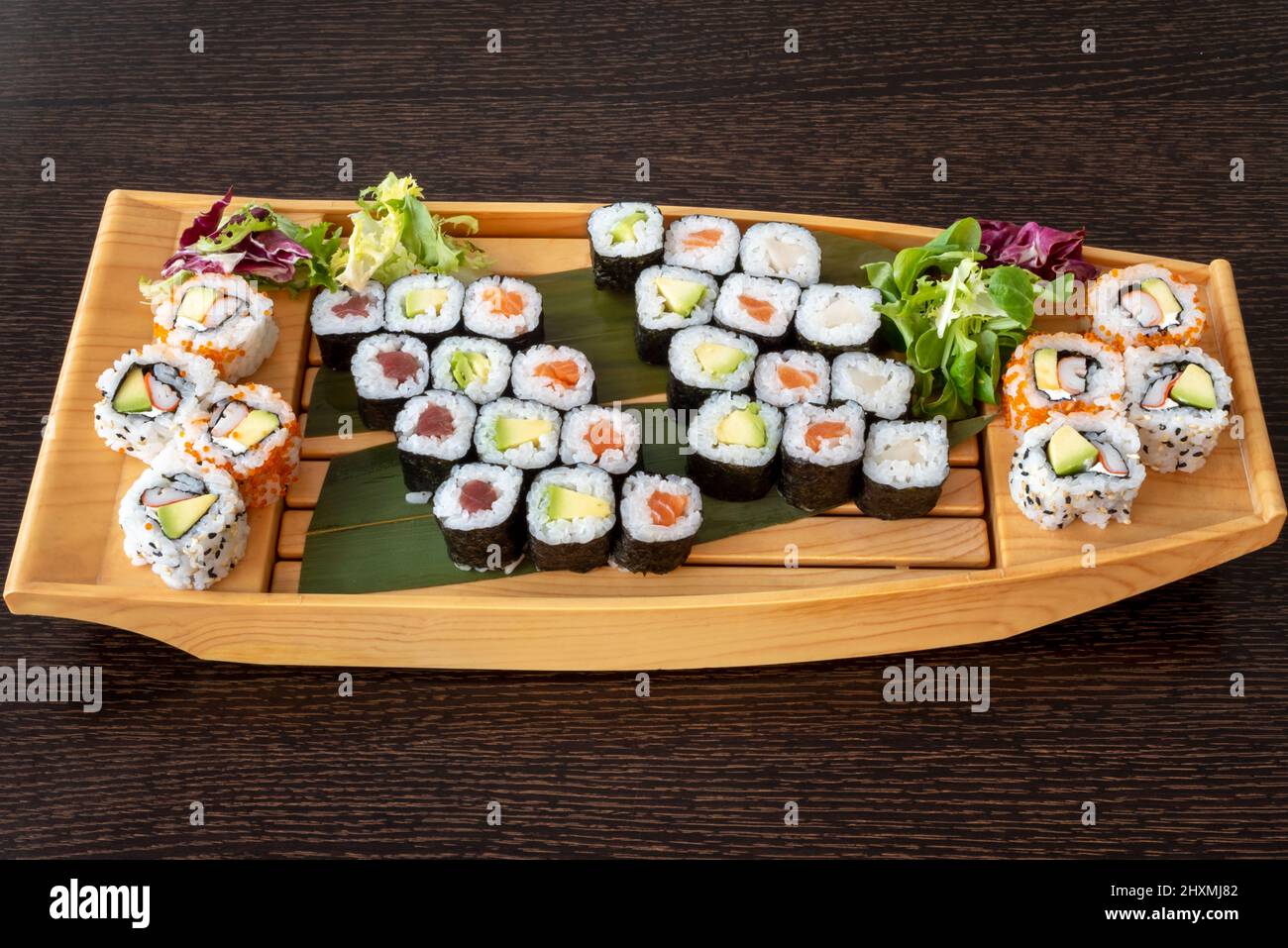 Sushi tray in the shape of a Japanese wooden boat with uramaki ...