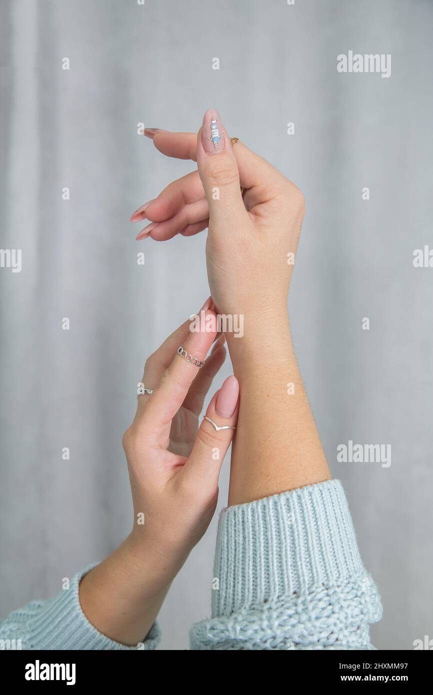 Women's hands with beautiful manicure and rings are folded in a ...