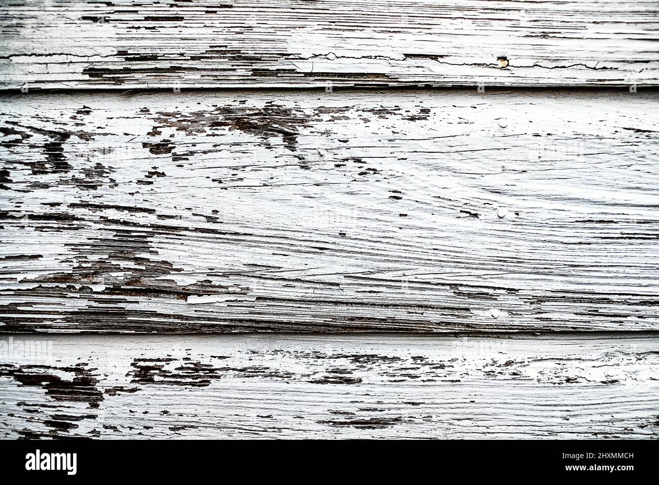 A closeup of aged, distressed wooden planks with chipping white paint ...