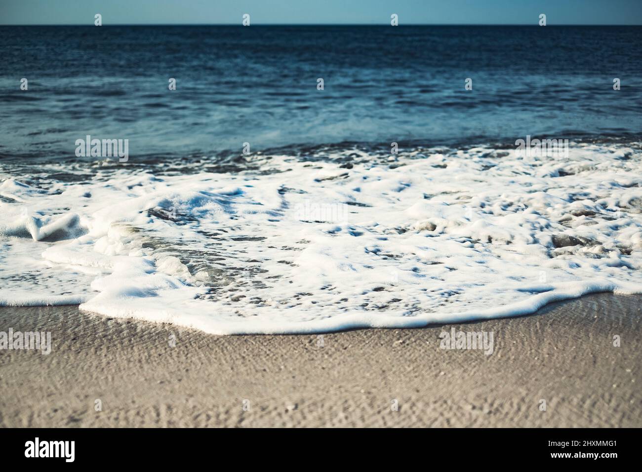A beautiful sandy beach as the wavy blue ocean rises to high tide Stock ...