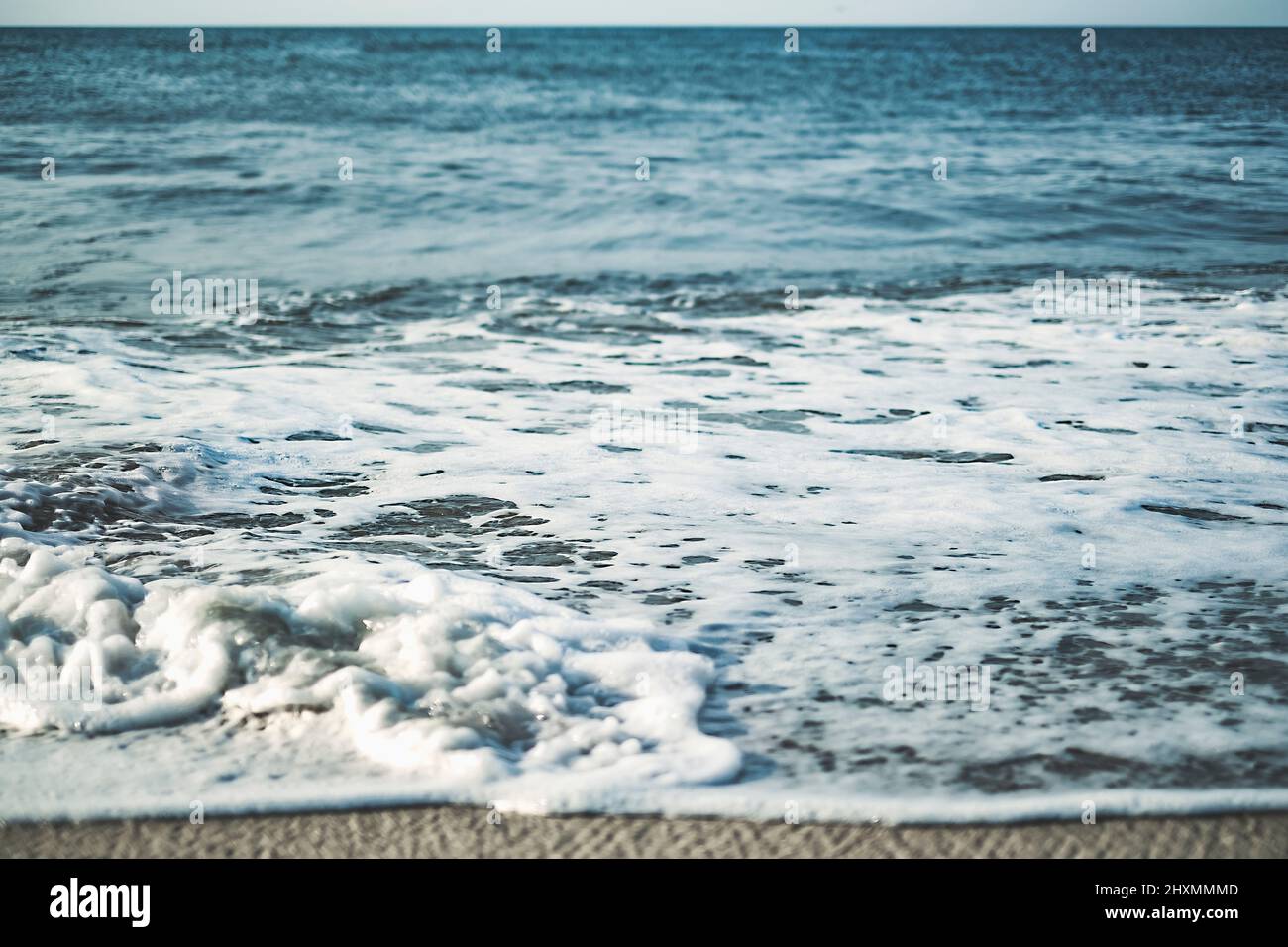 A beautiful sandy beach as the wavy blue ocean rises to high tide Stock ...