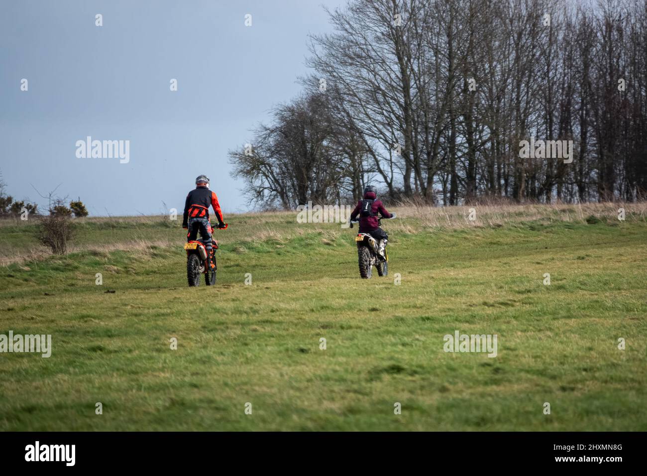 a pair of motor cyclists (bikers) riding off-road motorbikes across ...