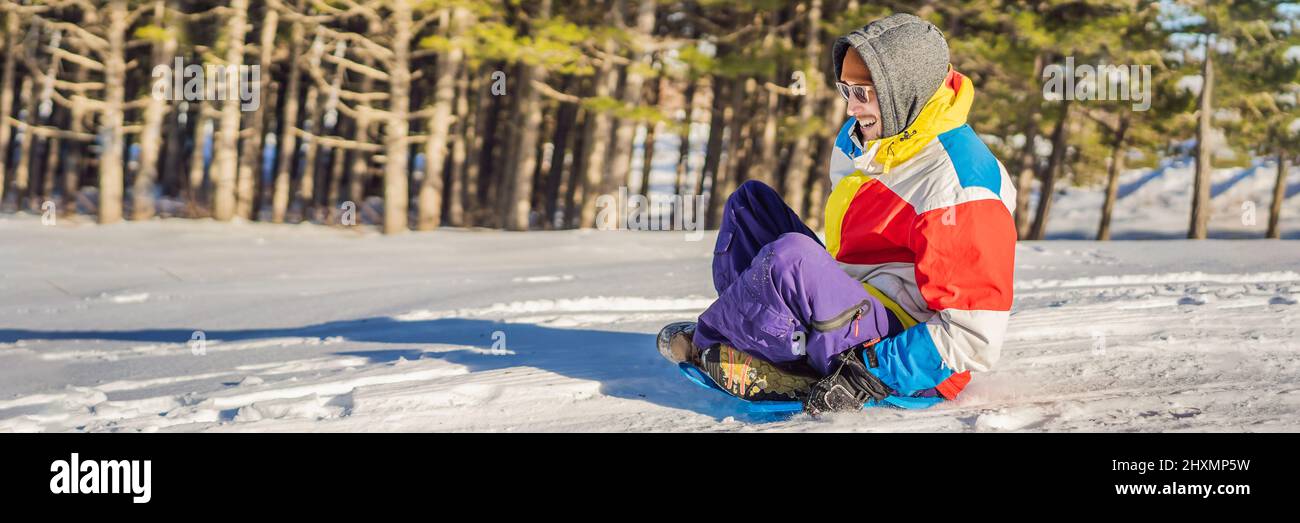 Cheerful man sledding down a snowy slope in full speed BANNER, LONG ...