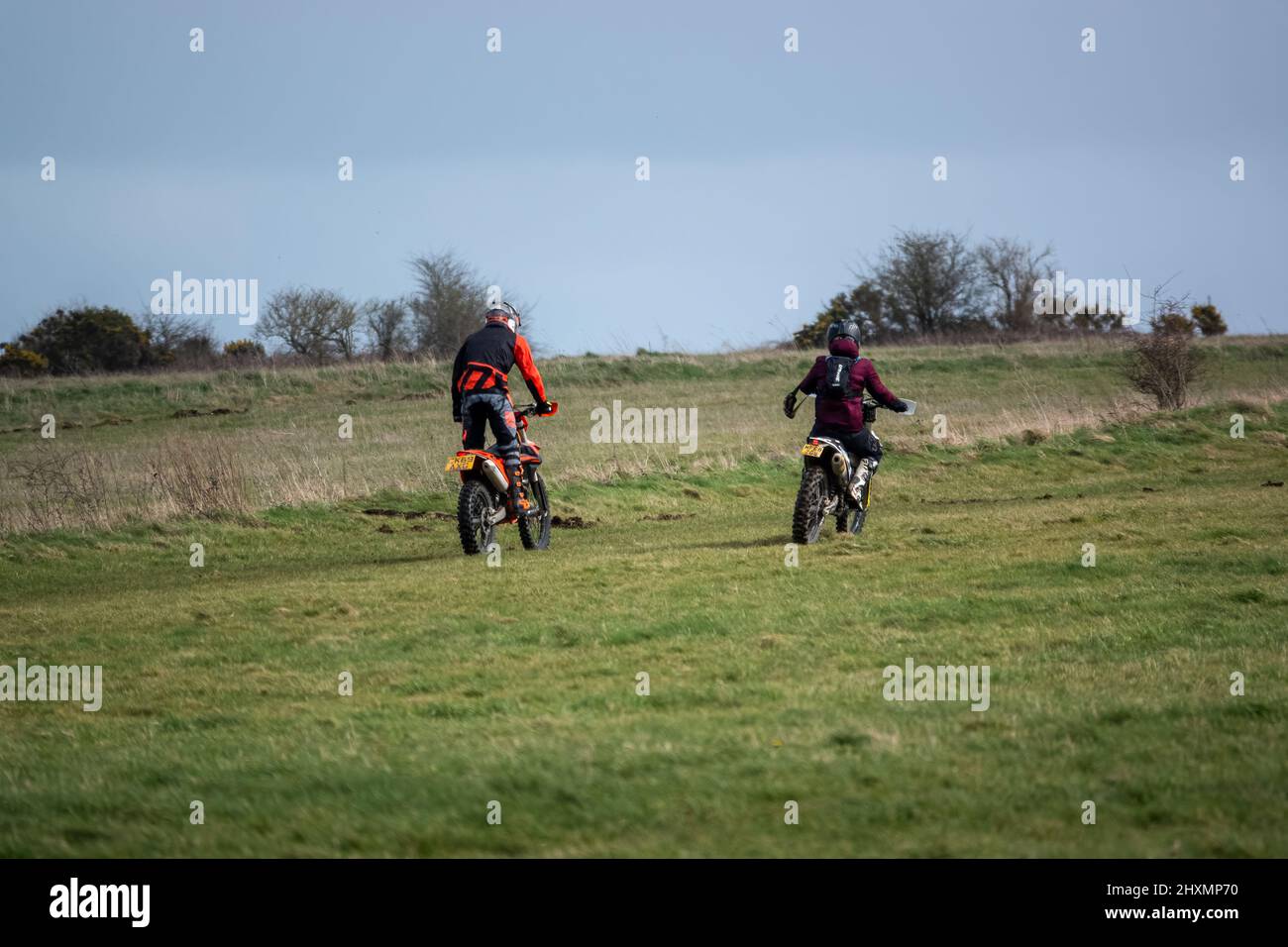 a pair of motor cyclists (bikers) riding off-road motorbikes across ...