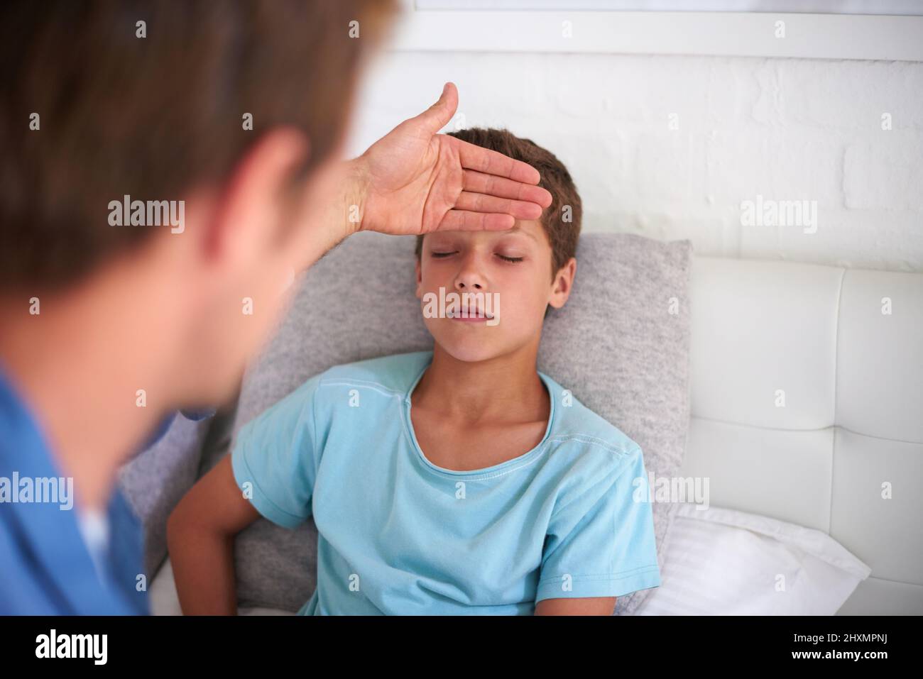 Feels like a fever. Shot of a father taking care of his sick little boy ...