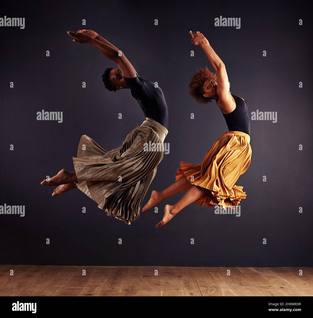 Synchronisity. Two contemporary dancers performing a synchronized leap ...