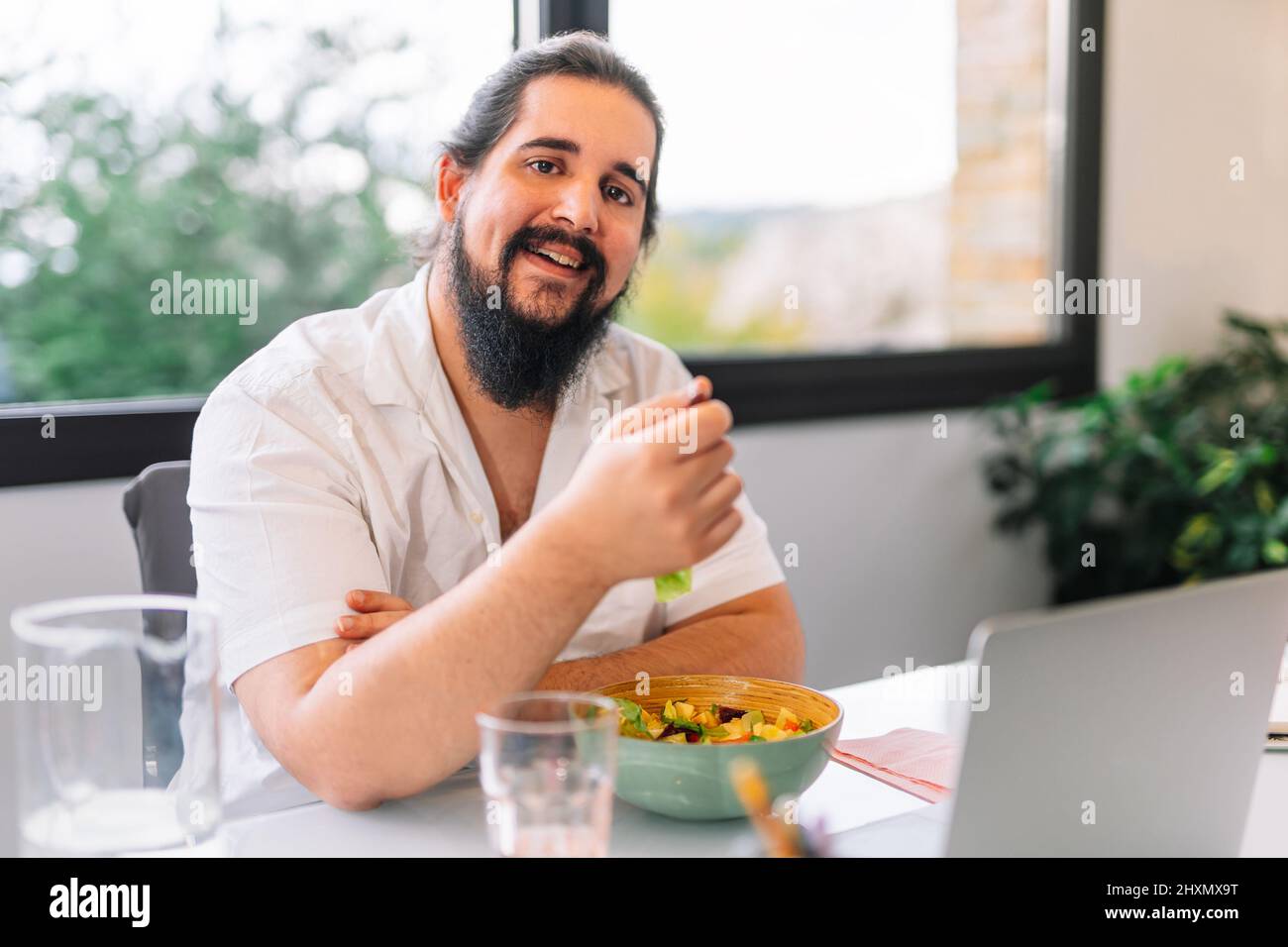 portrait of young man with beard while eating salad, smiling Stock ...