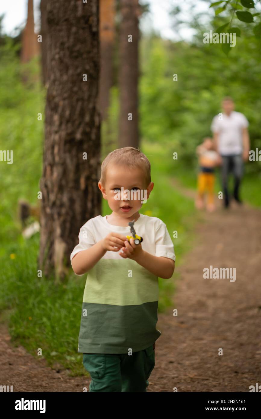 Adorable little Caucasian boy in the forest against the background of ...