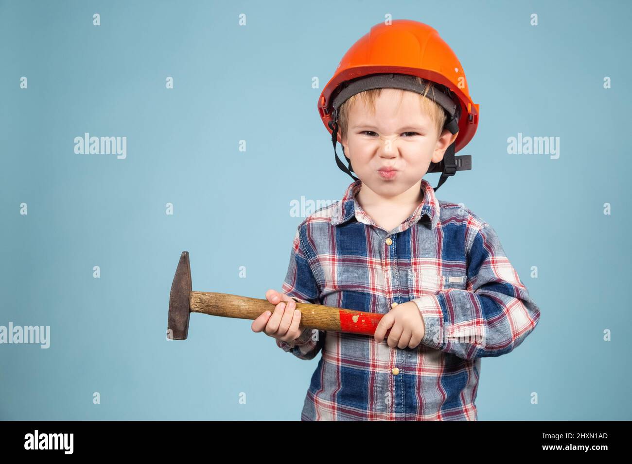 Adorable caucasian child is wearing orange safety helmet,holdings ...