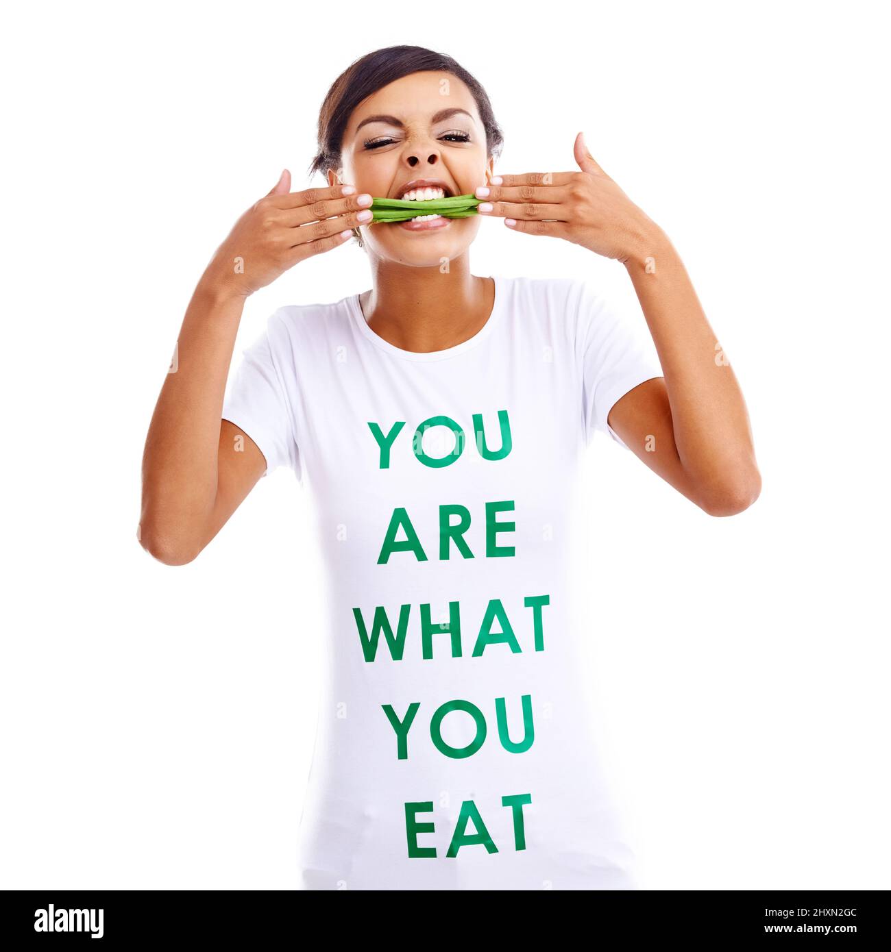 Om nom nom. Portrait of a young woman holding green beans while wearing ...