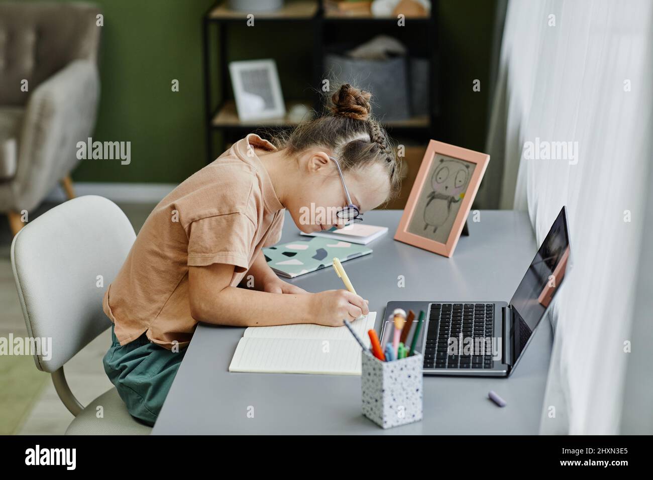 Side view portrait of young girl with down syndrome studying at home ...