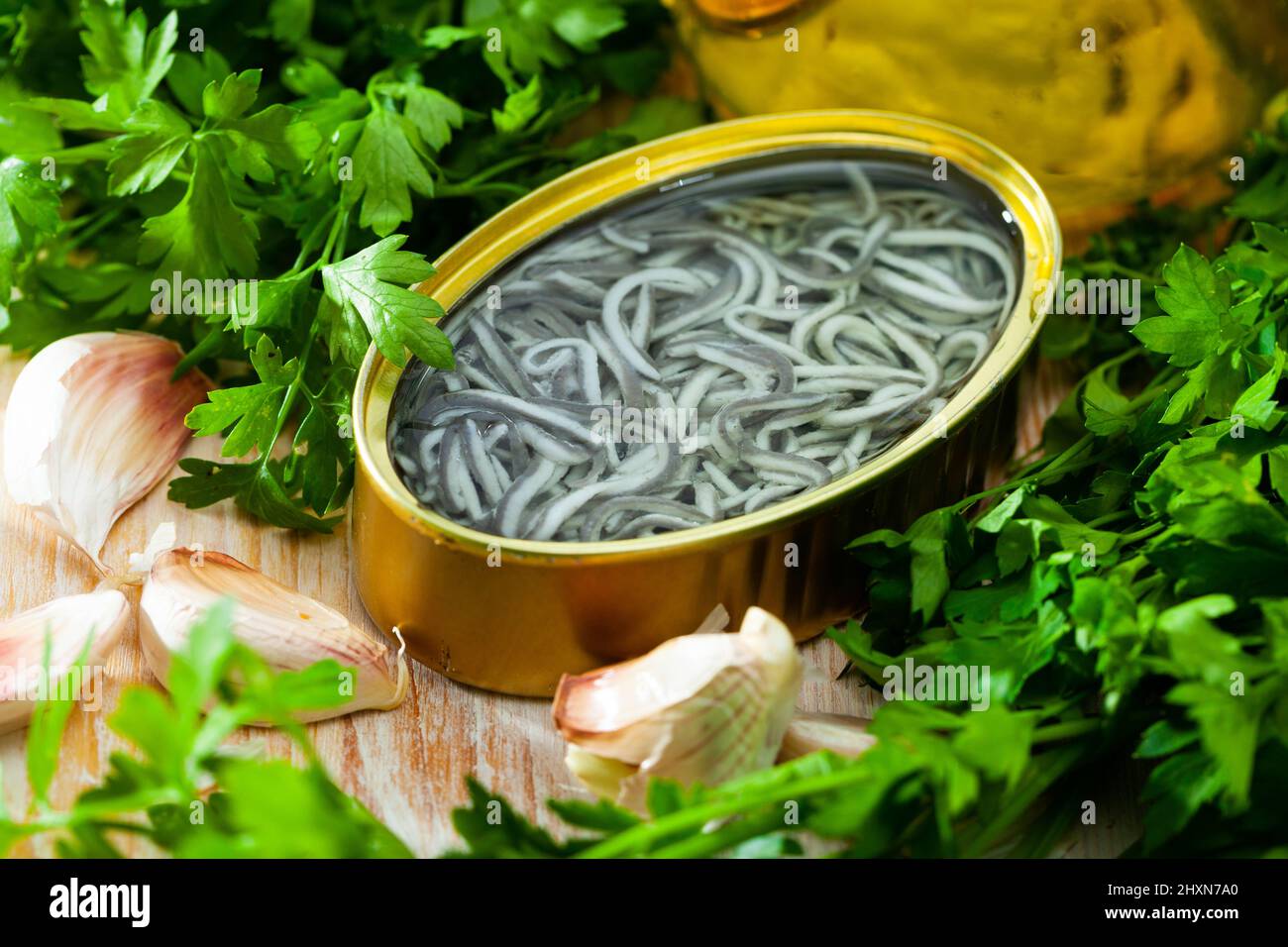 Pickled eels on background with garlic and greens at table Stock Photo ...