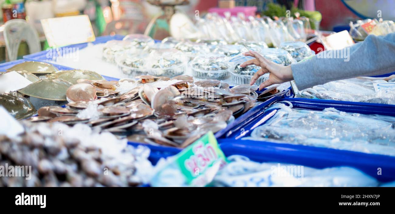 Female customers choosing fresh raw shellfish seafoods from large ...