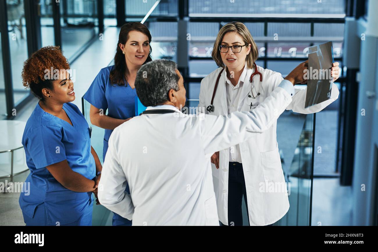 Patient health is a team effort. Shot of a team of doctors discussing ...